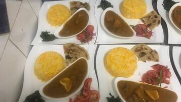 Uma mesa com vários pratos de comida, cada um contendo arroz, um prato de carne, pão achatado e um acompanhamento de legumes.