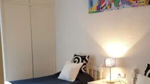 Quarto com duas camas, uma mesa de cabeceira com abajur e um quadro na parede.