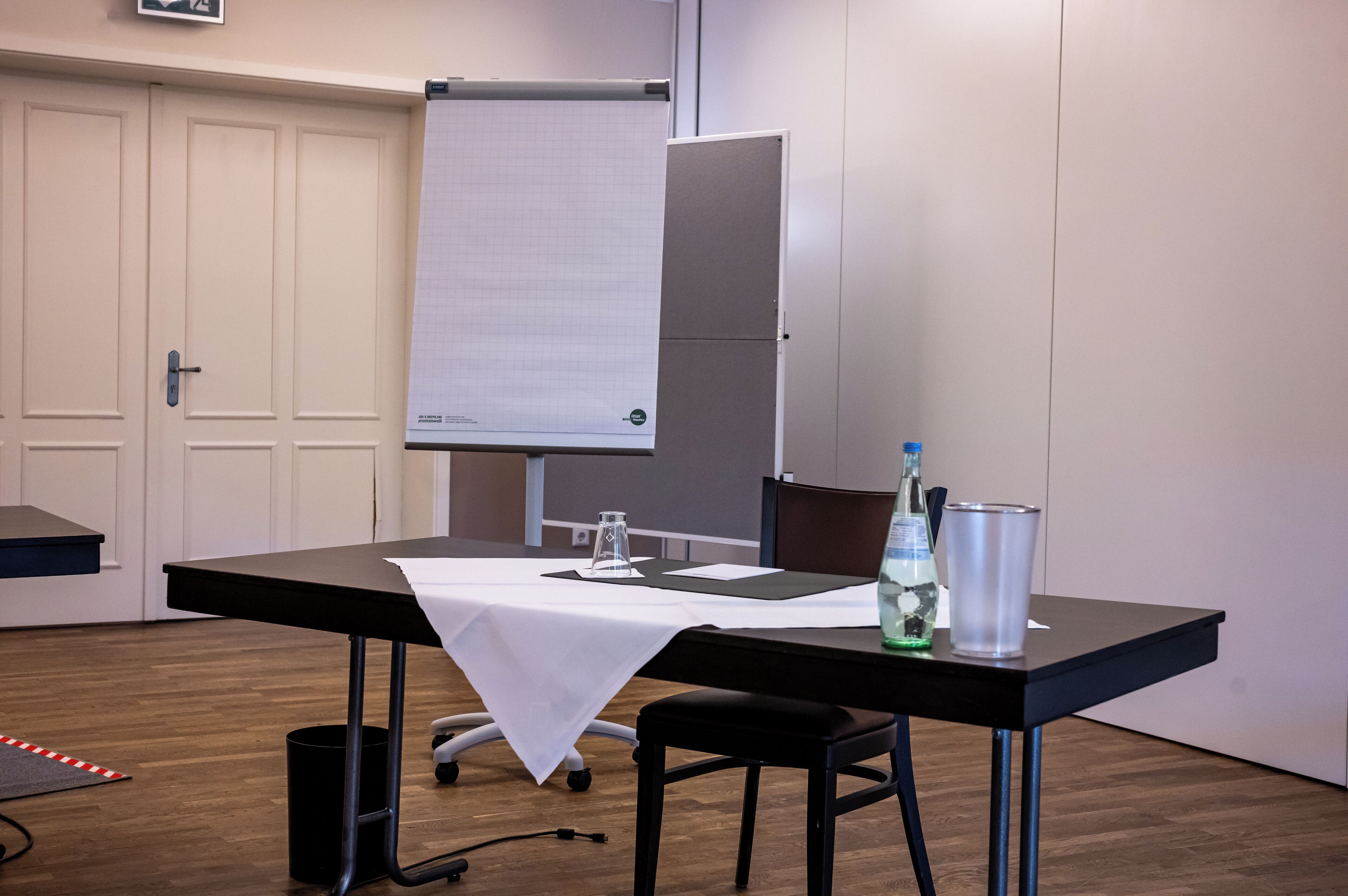 Uma sala de conferências com uma mesa, cadeiras, tela de projetor e quadro branco.