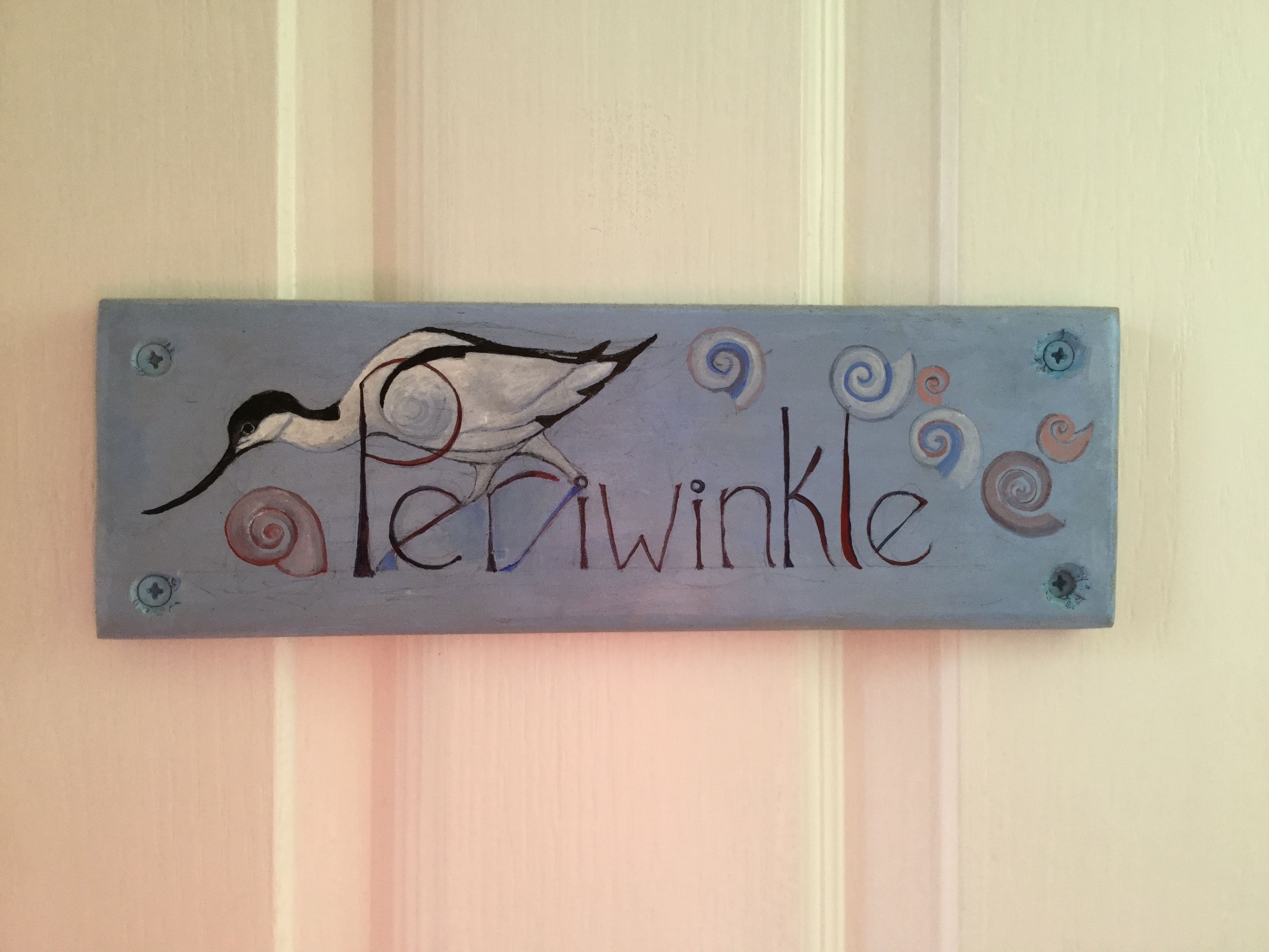 Um letreiro decorativo com um pássaro e a palavra "Pebwinkle" em uma parede.