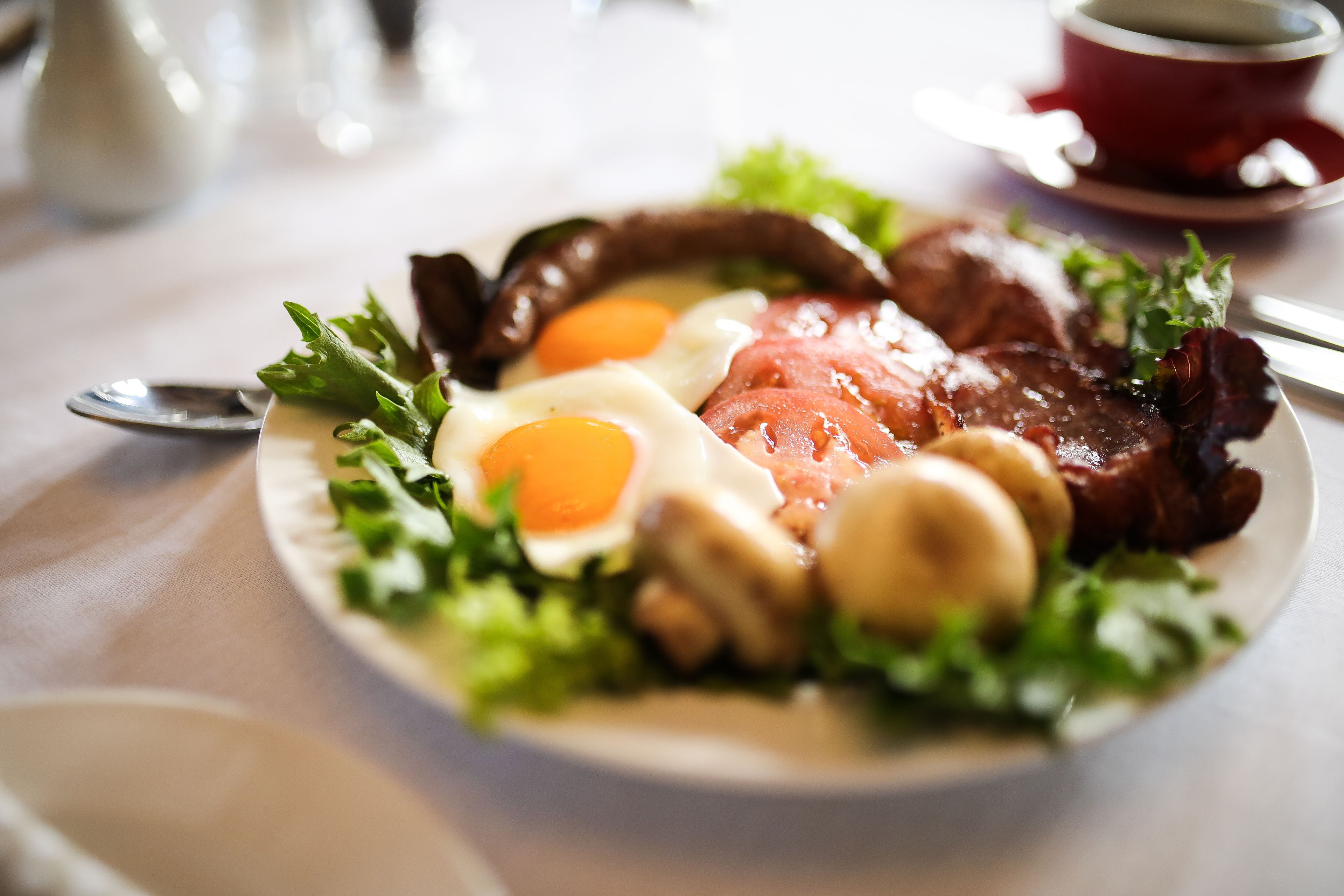 Prato de café da manhã com ovos, bacon, tomates e verduras.