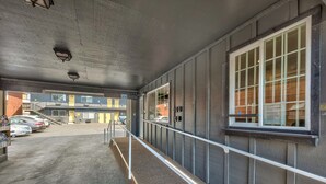 Uma área de estacionamento coberta com grade de metal, escadas e vista para um edifício com uma janela grande.
