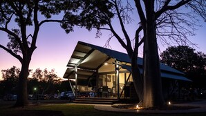 Uma casa moderna com um alpendre amplo, rodeada por árvores.