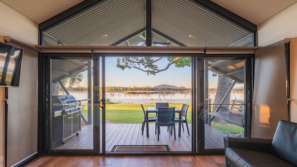 Interior moderno com uma grande porta de vidro deslizante que dá para um deck externo com churrasqueira e área de refeições.