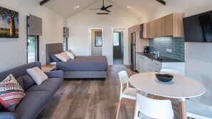 Um espaço de estar moderno e compacto, com sofá, cama, mesa de jantar e cozinha.