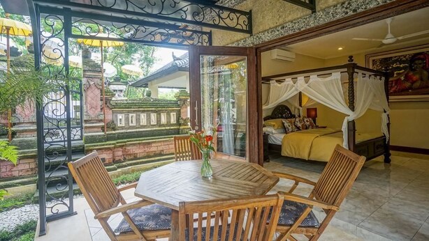 Um quarto com cama, porta de vidro que dá para o exterior e uma mesa com cadeiras.