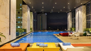 Piscina interna com vista para um edifício alto à noite.