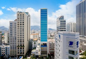 Paisagem urbana com o edifício Libra Hotel em destaque, apresentando um design moderno, rodeado por outros edifícios altos.