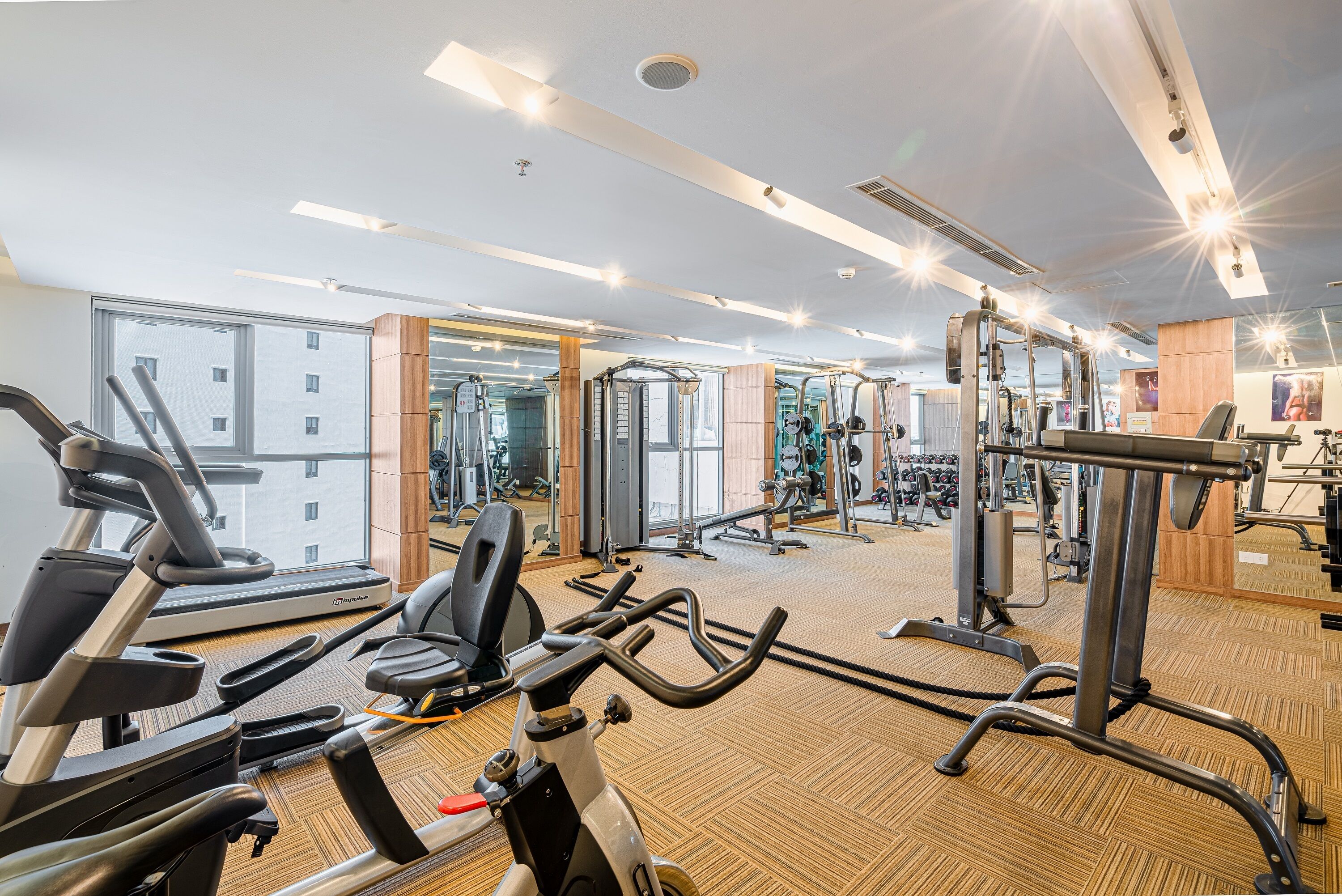 Uma academia com aparelhos de cardio, equipamentos de musculação e espelhos.