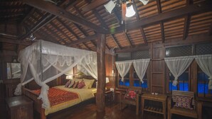 Quarto com teto de madeira, cama com dossel e janela com cortinas.