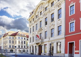 Um edifício histórico com arquitetura ornamentada, uma entrada imponente e uma bandeira.