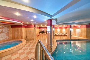 Um saguão de hotel com piscina, piso xadrez e uma área de recepção.