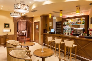 Uma área de bar com móveis de madeira, balcão e diversos garrafas e copos.