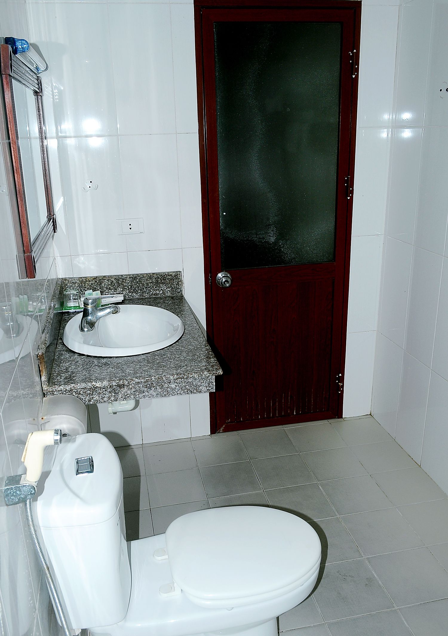 Casa de banho com uma pia branca, sanita e porta vermelha.