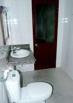 Casa de banho com uma pia branca, sanita e porta vermelha.