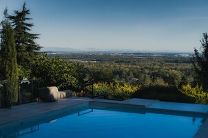 Piscina com vista para uma paisagem arborizada e montanhas ao longe.