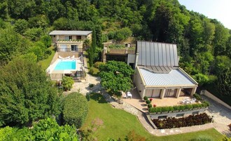 Uma casa grande com piscina, cercada por vegetação exuberante e colinas.