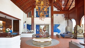 Um hall com recepção, uma fonte decorativa central e uma área de estar com sofá e poltronas.