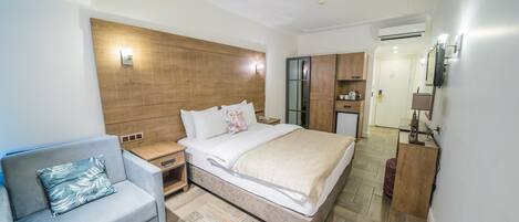 Quarto de hotel moderno com cama, sofá, mesa de cabeceira, armário e ar condicionado.
