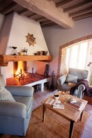 Uma sala de estar acolhedora com lareira, um sofá confortável, uma mesa de centro de madeira e uma estante de livros.