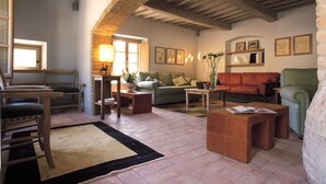 Uma sala de estar acolhedora com lareira, um sofá verde, uma mesa de centro de madeira e revestimento de pedra ao redor da lareira.