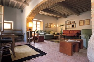 Uma sala de estar acolhedora com lareira, um sofá verde, uma mesa de centro de madeira e revestimento de pedra ao redor da lareira.