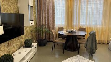 Uma sala de estar com televisão de tela plana, uma mesa de jantar redonda e um tapete aconchegante.