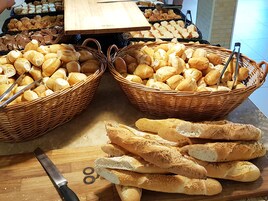 Uma tábua de corte de madeira com uma faca, cestas de pão e outra tábua de corte de madeira com uma faca.