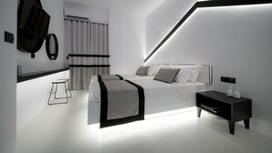 Quarto moderno com cama, mesa de cabeceira e televisão na parede.
