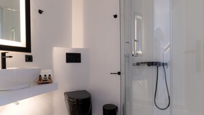 Um banheiro moderno com pia branca, box de vidro e ladrilhos no chão com padrão.