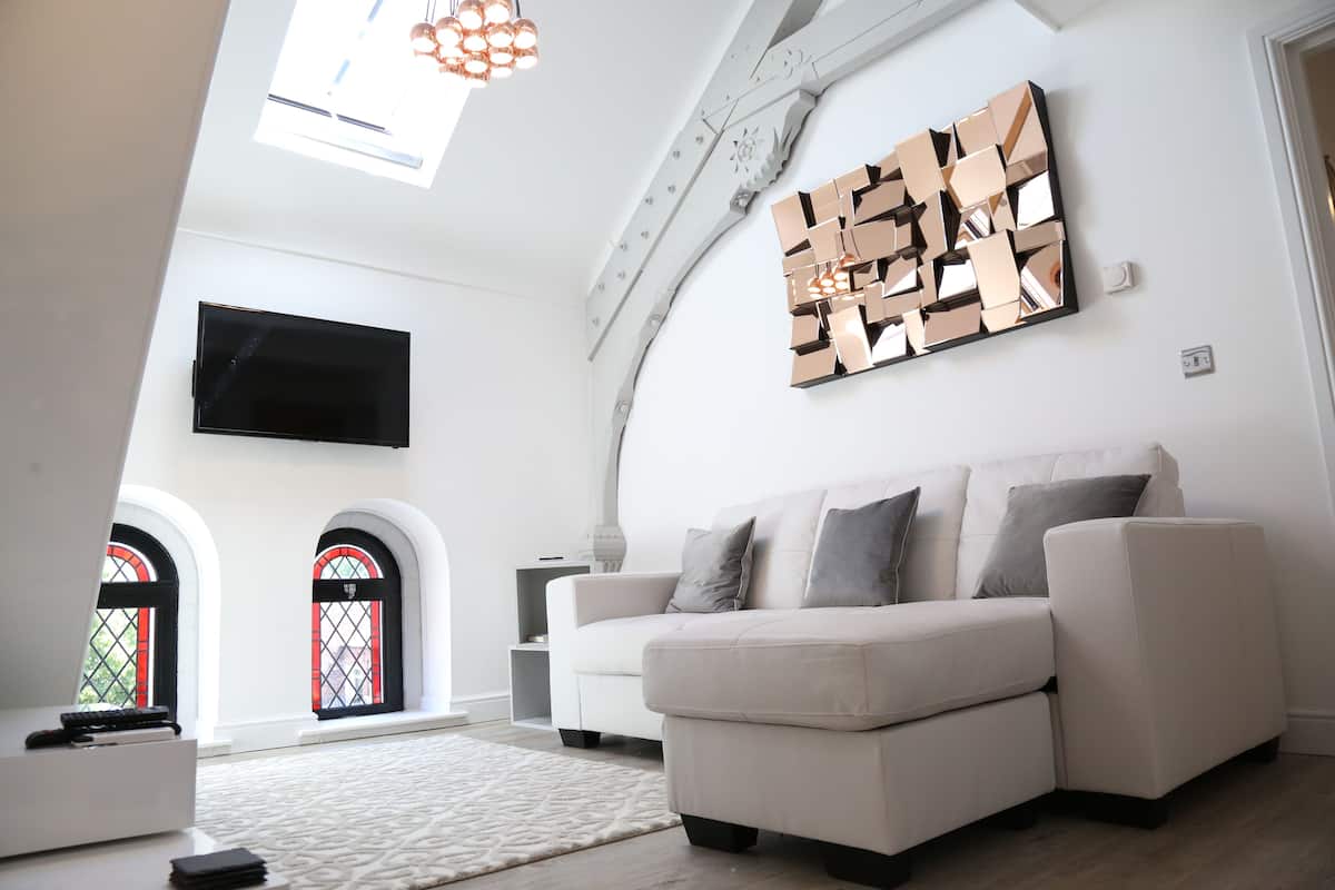 Uma sala de estar moderna com um sofá branco, uma televisão de tela plana e uma peça de arte original na parede.