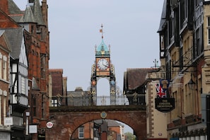 Uma torre de relógio histórica com uma ponte ao fundo.