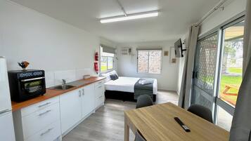 Quarto compacto com cozinha compacta, cama, mesa e janela.