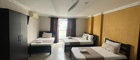 Quarto de hotel com duas camas, guarda-roupa e janela com cortinas.