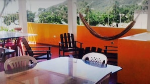 Um quarto com uma mesa, cadeiras e uma rede.
