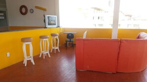 Quarto com parede amarela, sofá vermelho e três banquinhos de madeira.