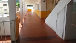 Um corredor com piso de azulejos, paredes brancas e detalhes em amarelo.