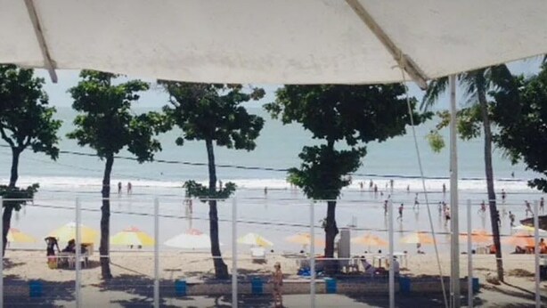 Uma praia com guarda-sóis e uma cerca.