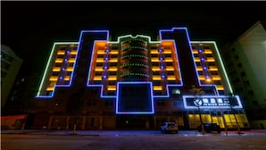 Um hotel com fachada iluminada por néon, vários andares e uma placa com texto.