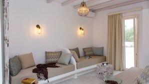 Um quarto acolhedor com um sofá, uma mesinha com uma tigela de frutas e uma janela com cortinas.