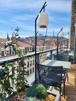 Terraço no telhado com área de estar ao ar livre, vista da paisagem urbana e um pequeno jardim.
