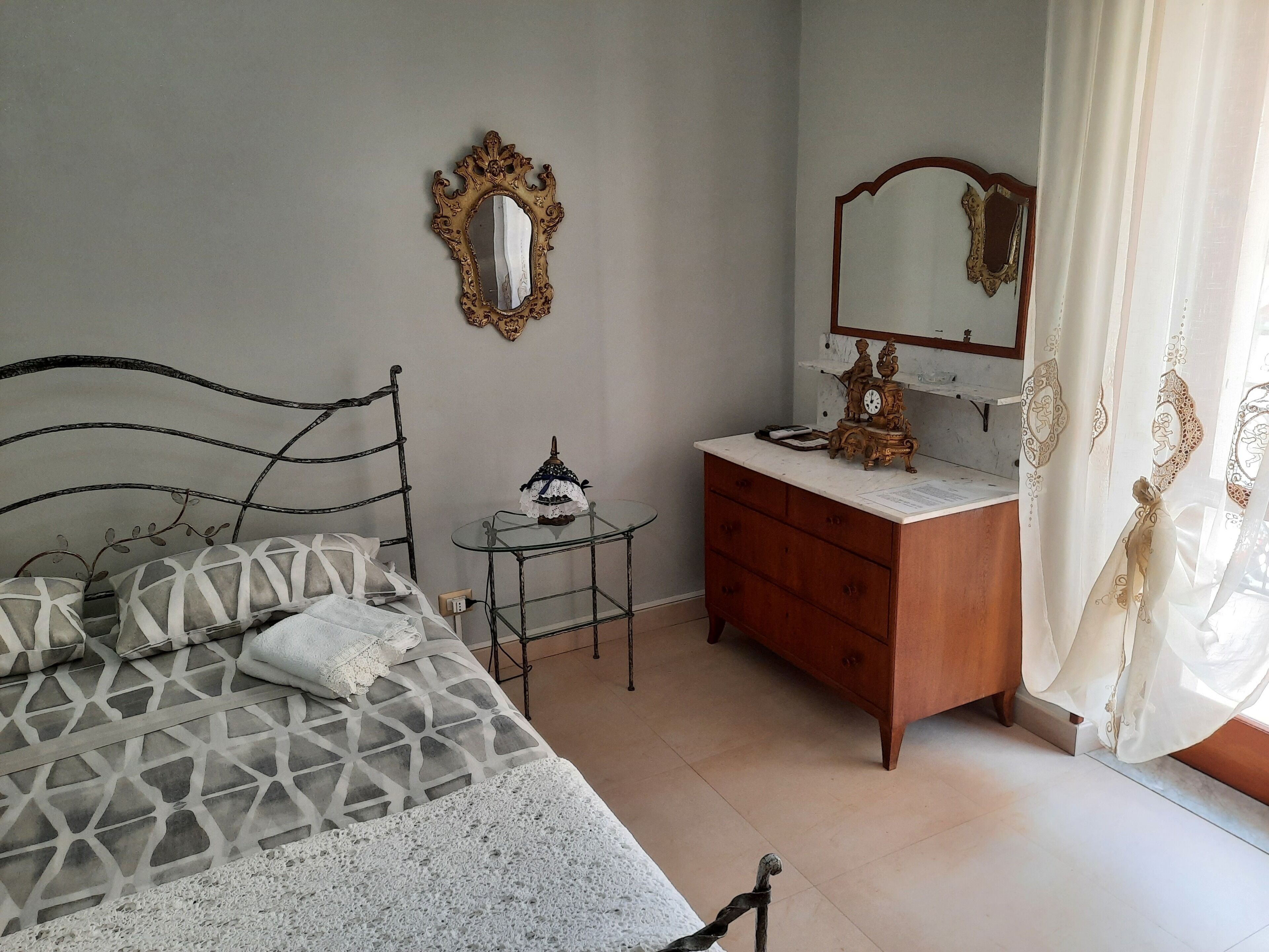 Quarto com cama, penteadeira e duas espelhos.