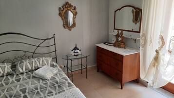 Quarto com cama, penteadeira e duas espelhos.