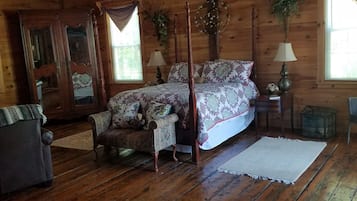 Quarto de cabana de madeira com cama, sofá, cadeira e espelho.