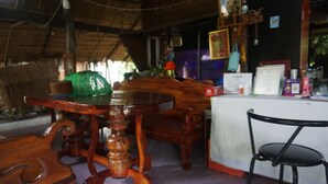Uma mesa de jantar de madeira com cadeiras, uma cadeira preta e um balcão com diversos objetos.