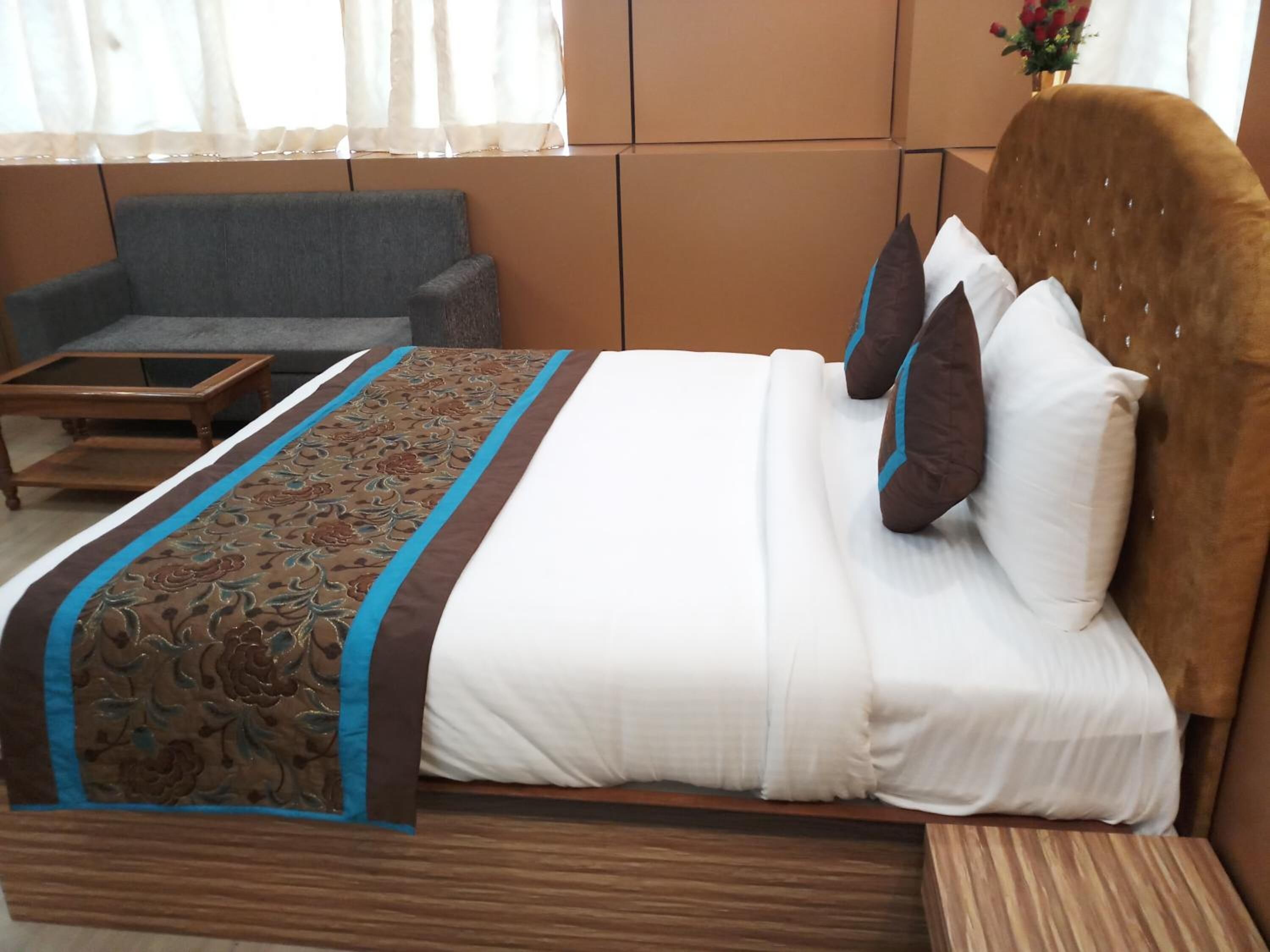 Cama bem arrumada com colcha estampada, cabeceira de madeira e dois travesseiros.