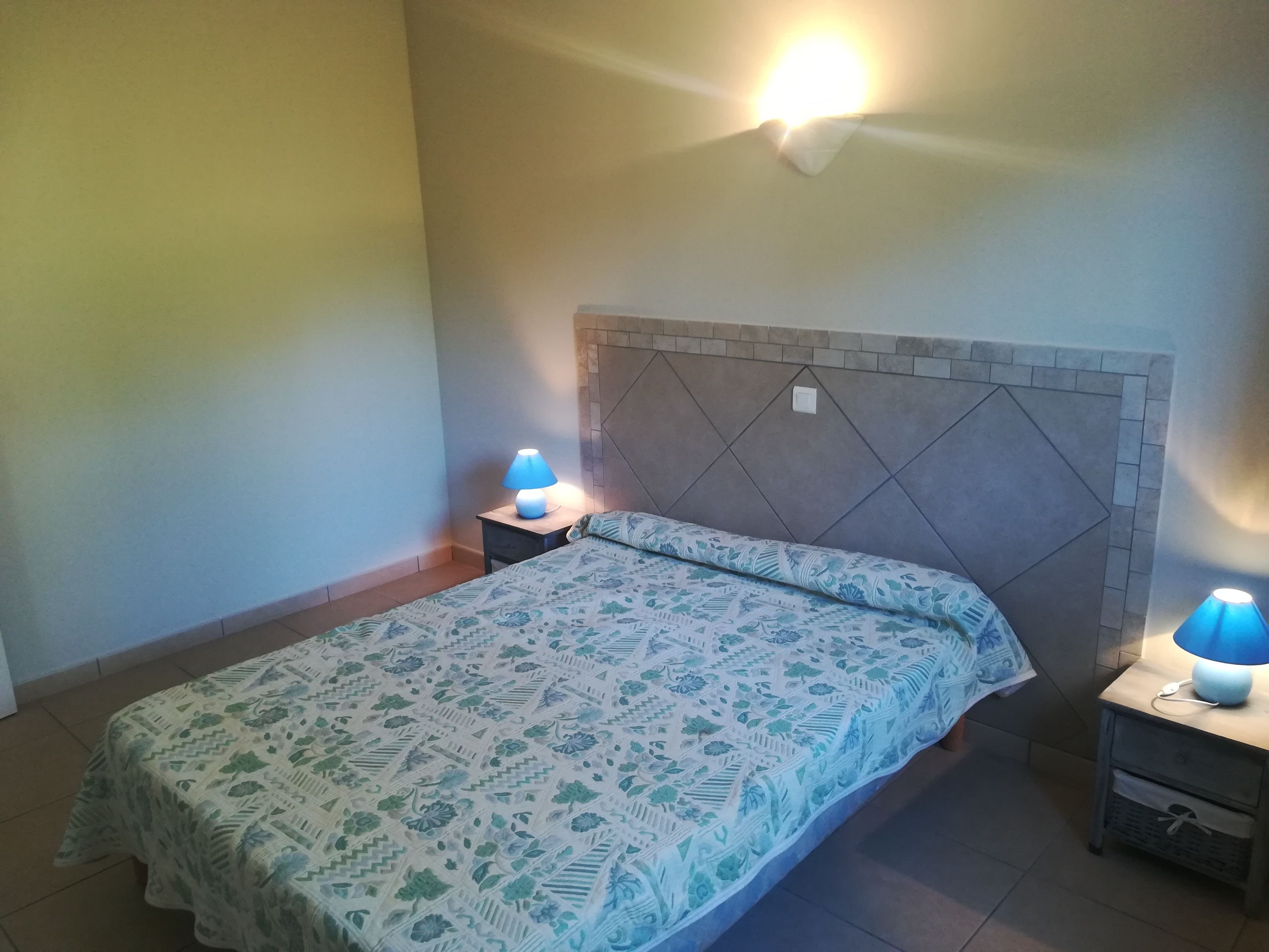 Quarto com uma cama, duas mesas de cabeceira e duas luminárias.