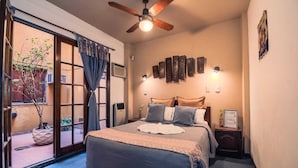 Quarto com cama, ventilador de teto, aquecedor fixado na parede e vista para o exterior.