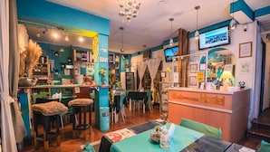 Uma área de bar acolhedora com balcão, assentos e uma tela de televisão.