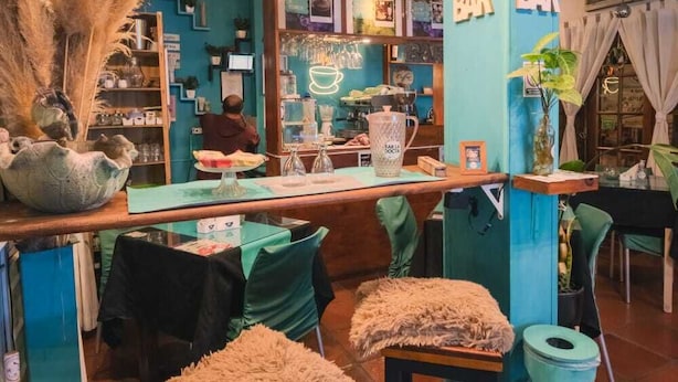 Uma área de bar com banquetas, um balcão e um letreiro de neon.